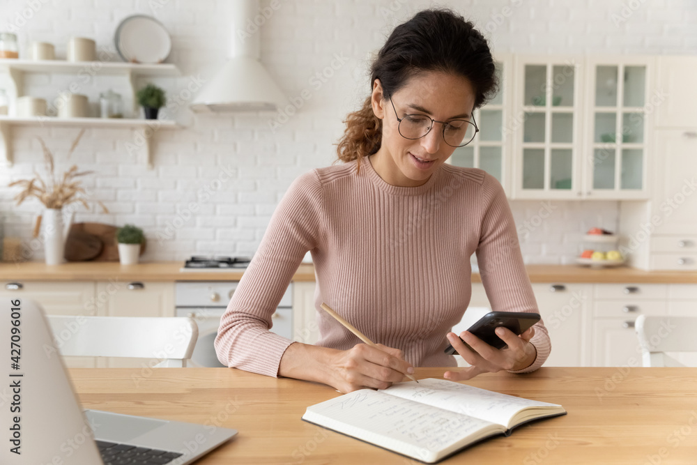 Using online open sources. Confident latina woman handwrite to notepad ...
