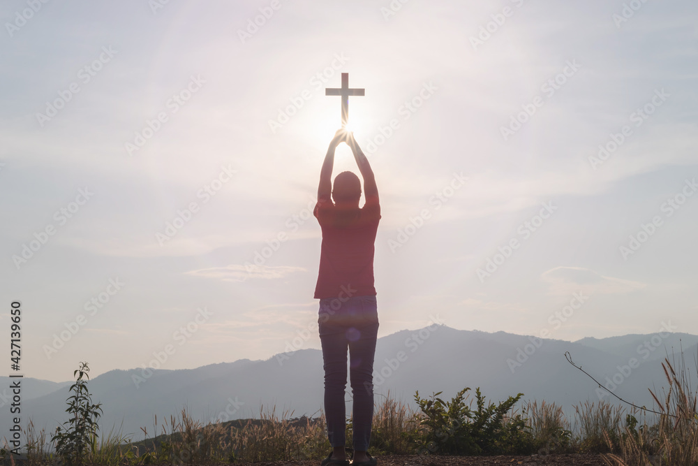 Silhouette of human praying and holding christian cross for worshipping ...