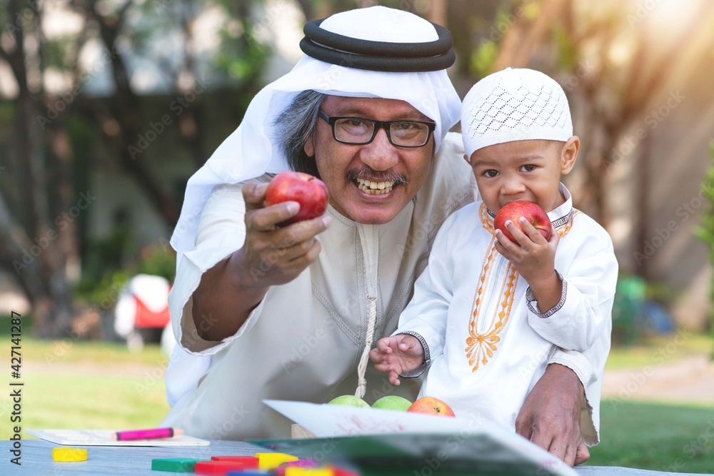 Foto de Asian Muslim man and Muslim boy with tradition suit eating red ...