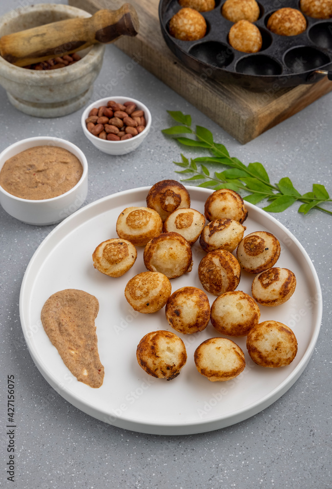 Suji appe or appam served on a appam pan with peanuts and tamarind ...