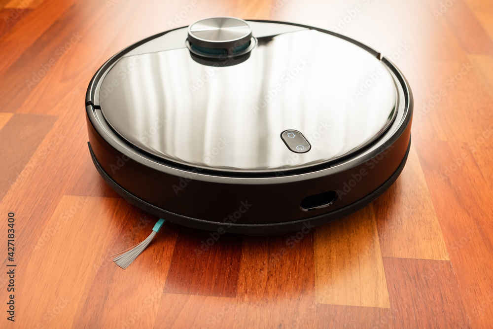 Black automatic vacuum cleaner robot in a house to clean the floor and ...