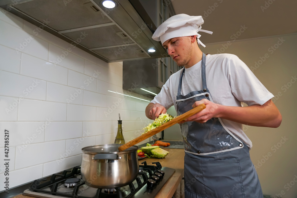 The chef in the kitchen opens the Pan. Steam is coming out of the pot ...