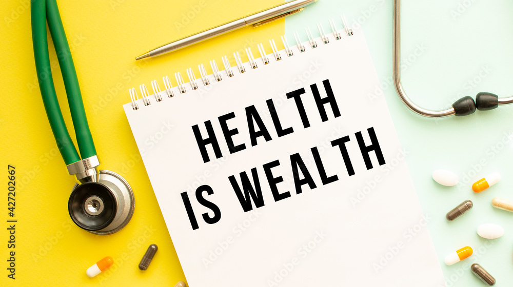 HEALTH IS WEALTH is written in a notebook on a color table next to ...