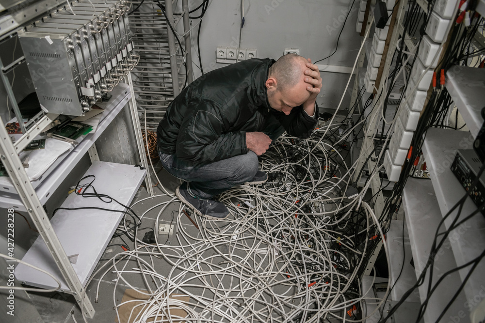 The man is in a plundered server room. A sad technician sits near a ...