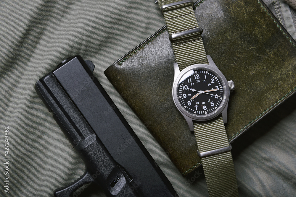 Vintage military watch with nato strap and pistol on army green ...