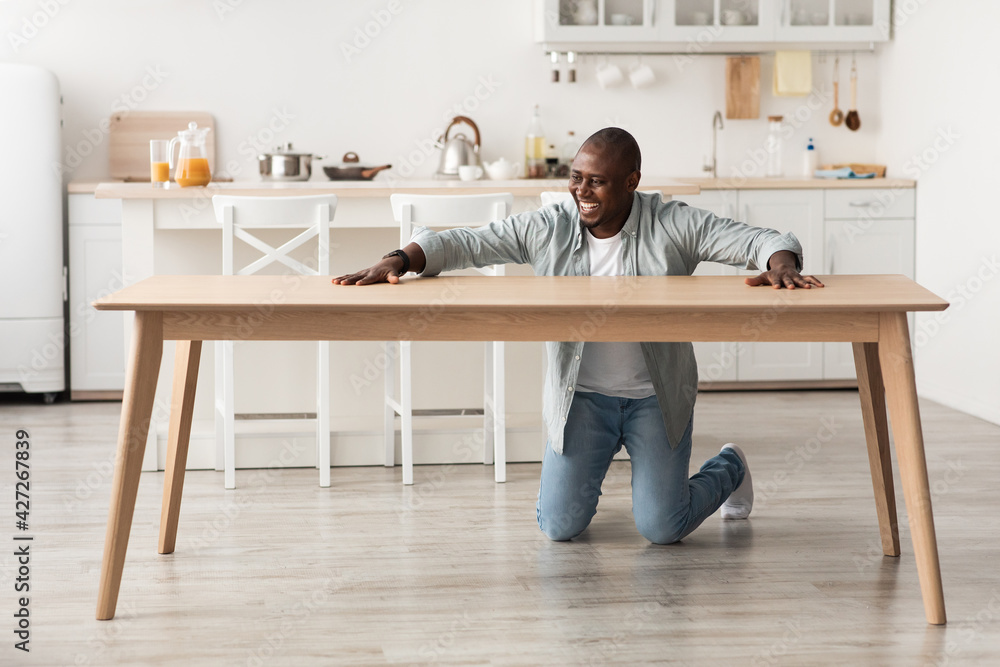 Overjoyed black man touching new wooden table, after assembing ...