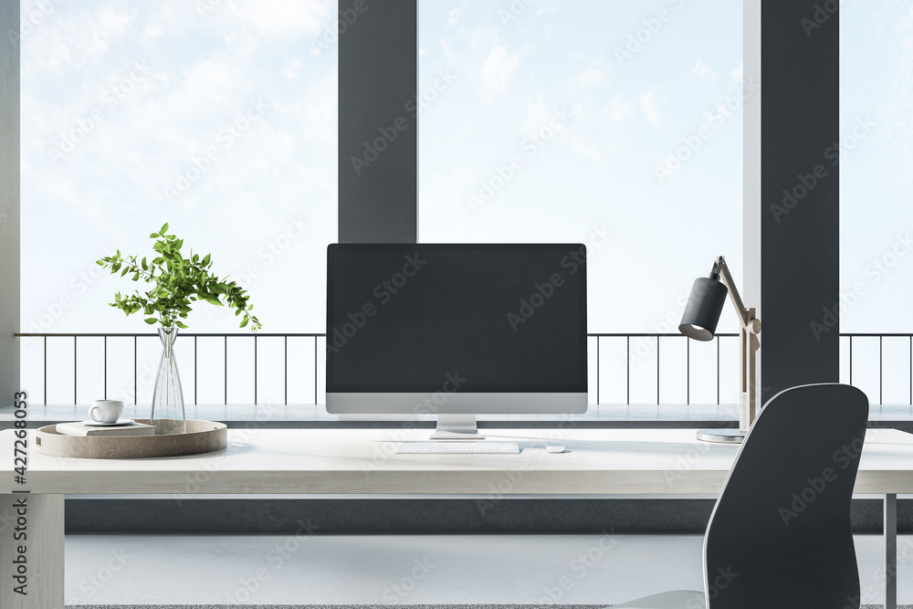 Pc standing on a desk in a bright room with black columns and big ...