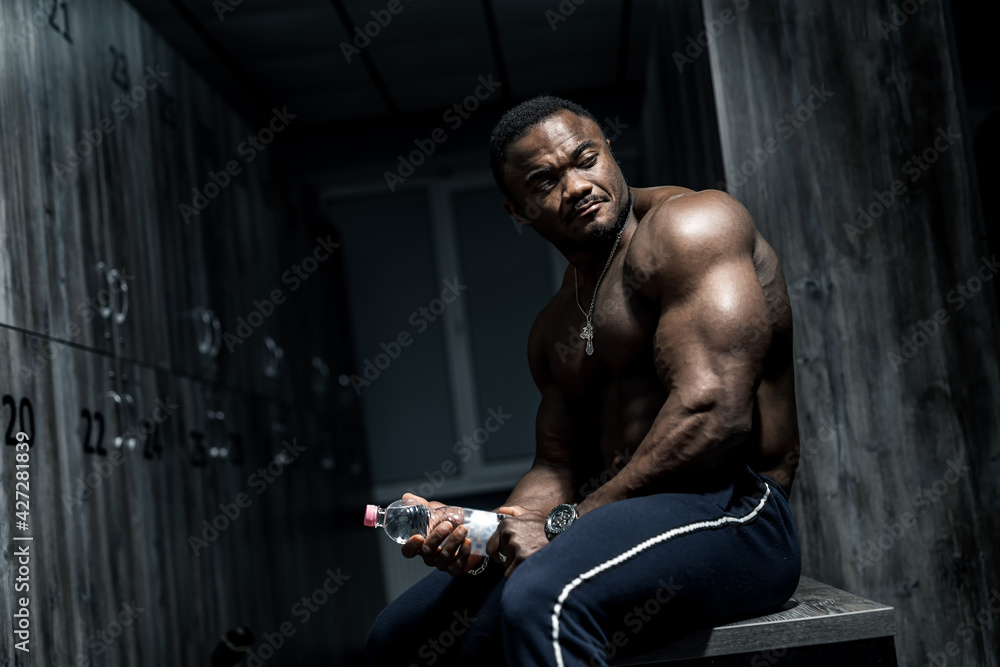 Muscular african male in locker room. Man having rest after heavy ...