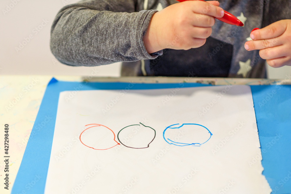 Little child develops fine motor skills, learns to draw circles. Close ...