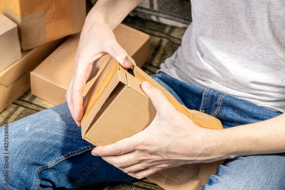 male person indoors unpack cardboard parcel package. men opening box ...