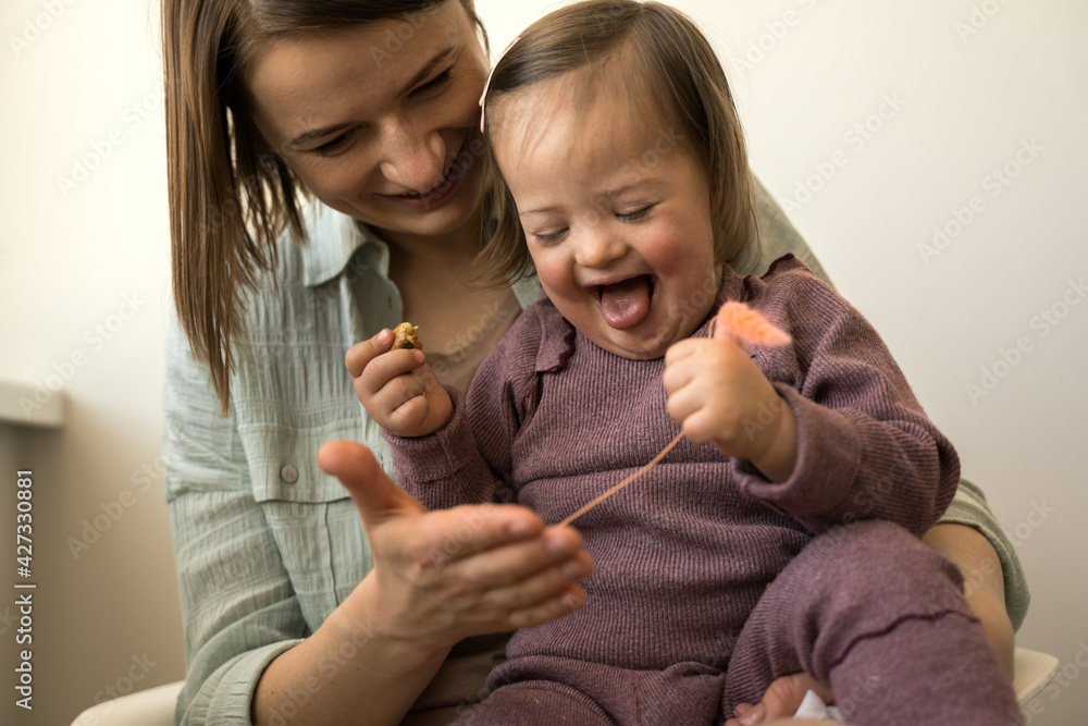 Girl with down syndrome sitting at the laps of her mother and having ...