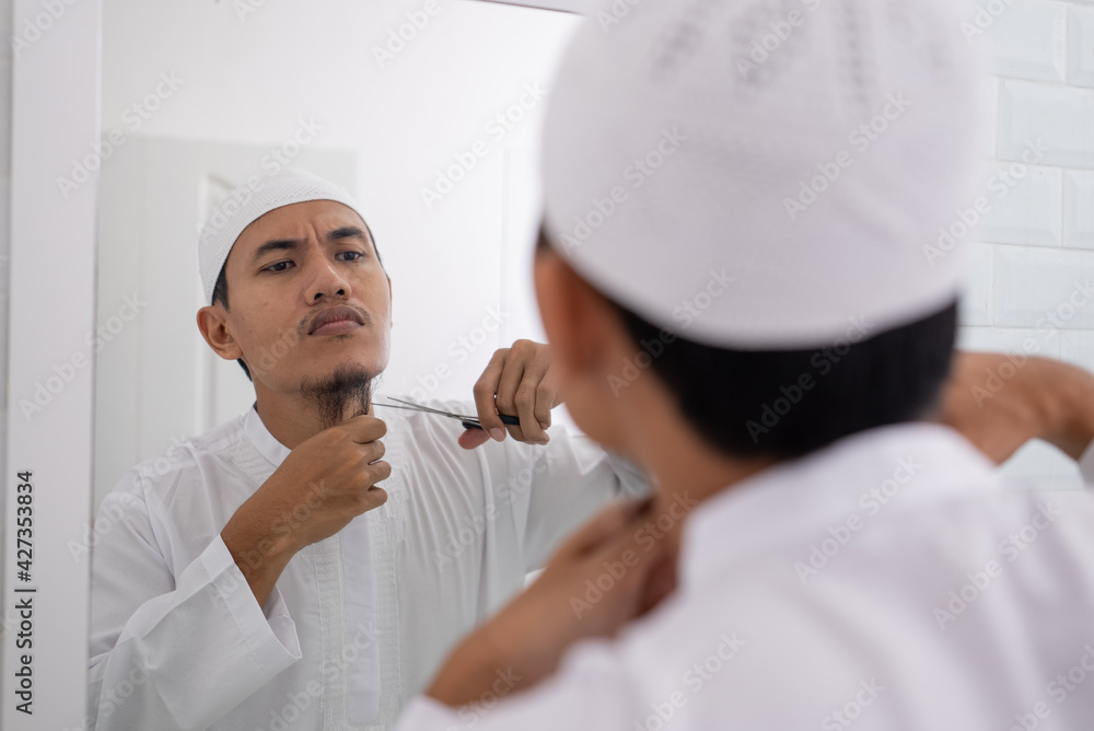 muslim asian man unsure to shave off his beard using scissor Stock ...