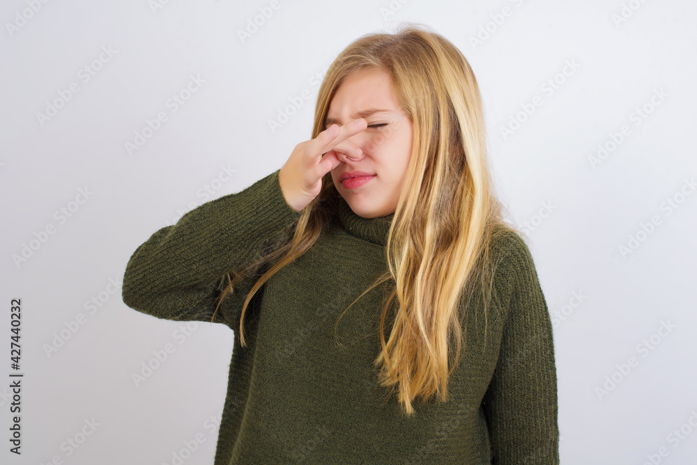 Caucasian kid girl wearing green knitted sweater against white wall ...