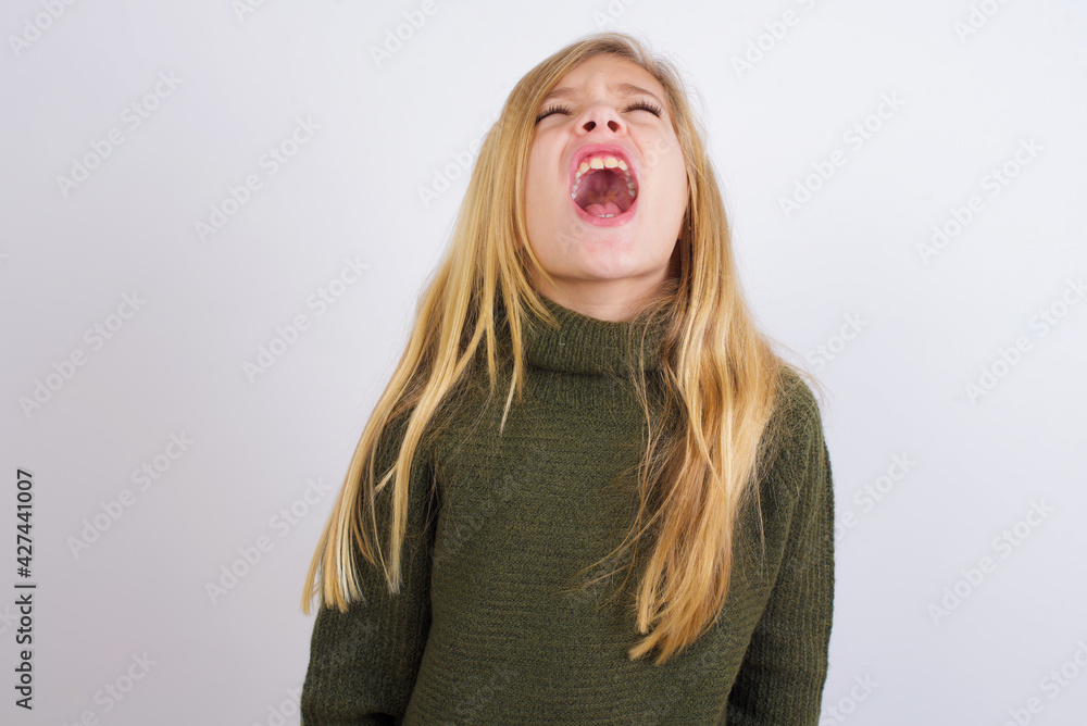 Caucasian kid girl wearing green knitted sweater against white wall ...