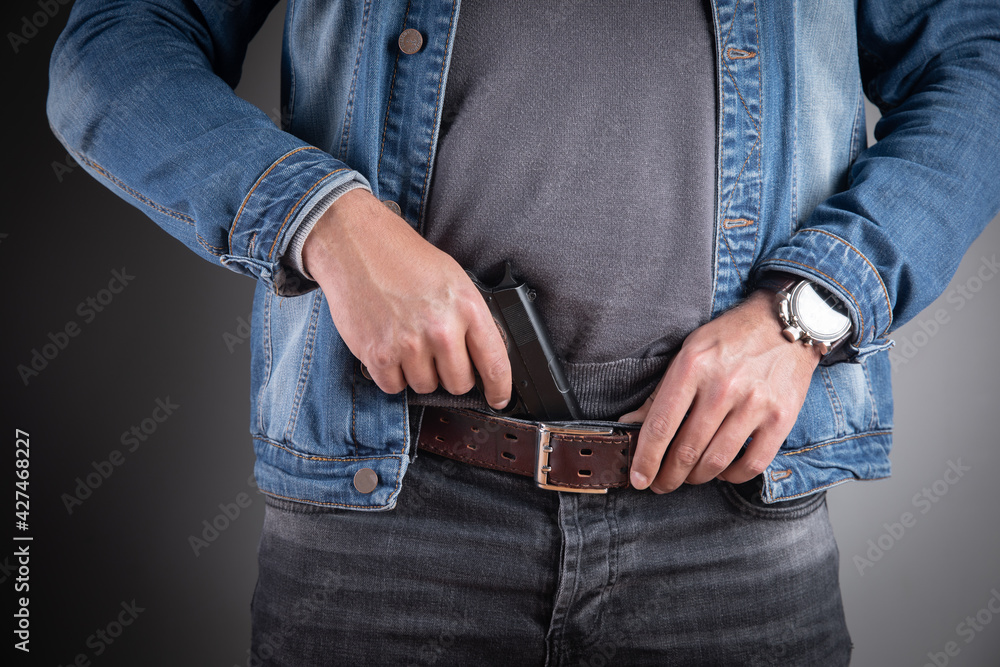 Man drawing concealed carry pistol Stock Photo | Adobe Stock