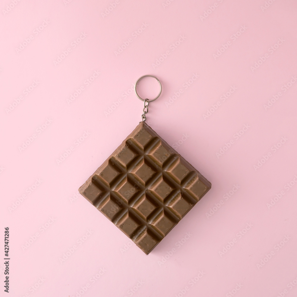 Chocolate as a key ring. Chocolate cube. Pink wallpaper. Minimal idea ...