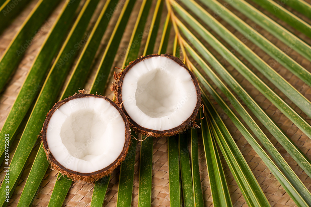 Coconuts cut in half and whole coconuts on coconut palm leaf background ...