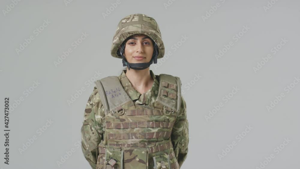 Young female soldier in uniform wearing body armour and helmet in front ...