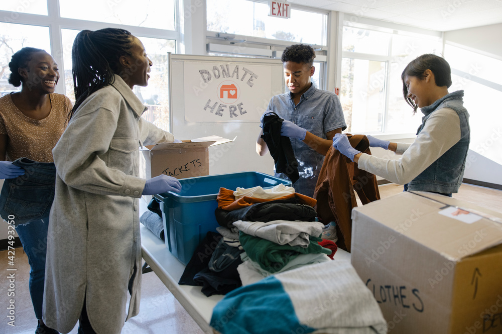 Teenage volunteers sorting clothing donations in community center Stock ...