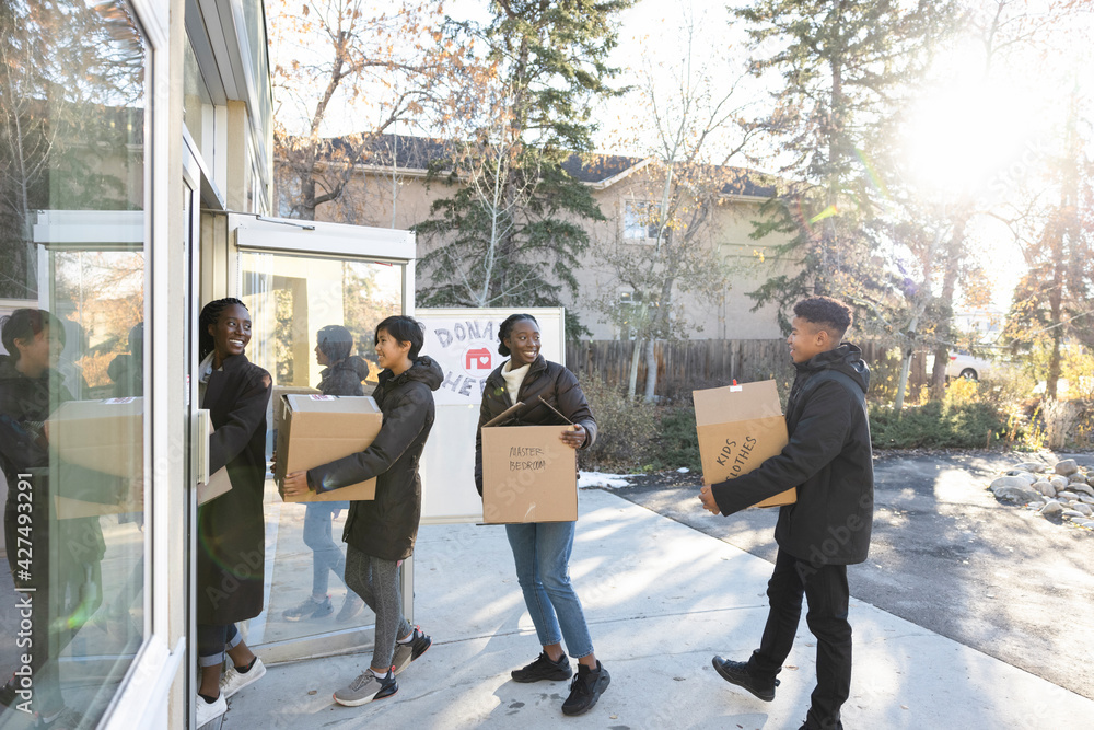 Teenage friends carrying donation boxes into community center Stock ...