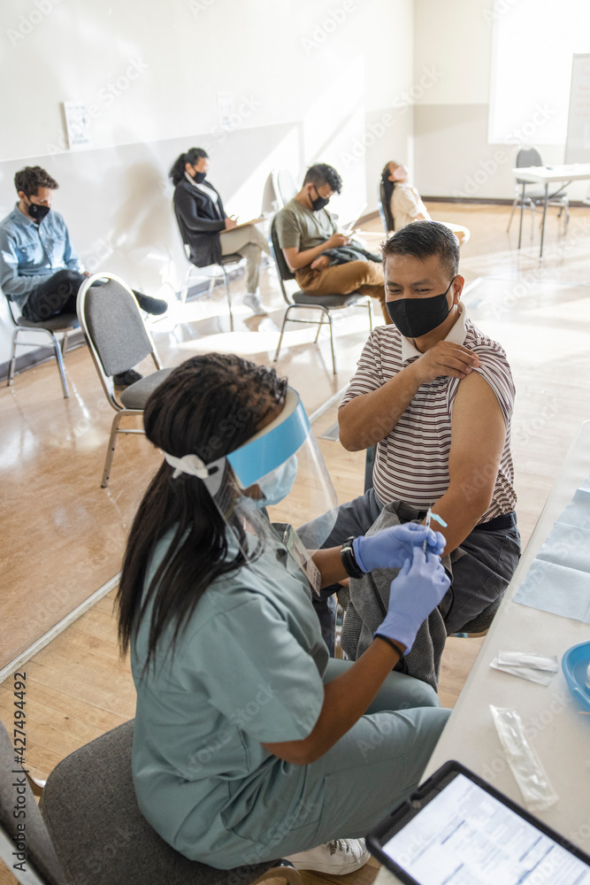Nurse in PPE giving patient COVID-19 vaccination in clinic Stock Photo ...