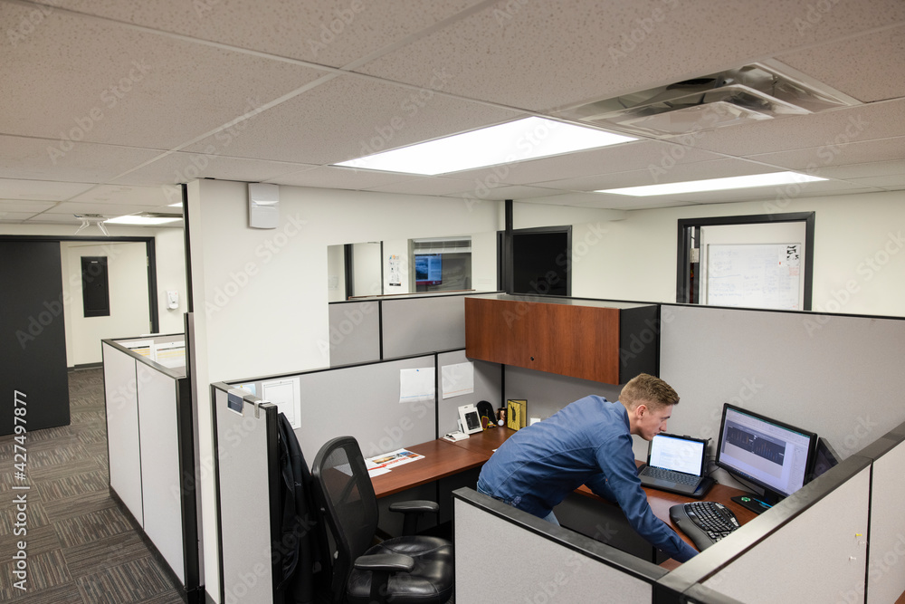 Man working at computer in office cubicle Stock Photo | Adobe Stock