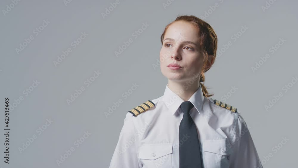 Serious young female airline pilot or ship captain wearing uniform ...