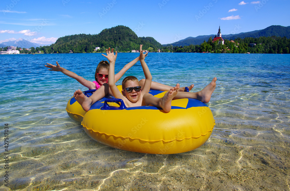 Boy and girl on inflatable float in lake. Little children floating in ...