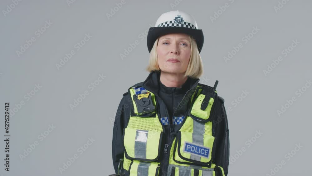 Serious mature female police office wearing uniform in front of plain ...