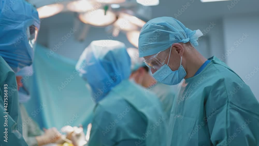 Operating theater. Team of doctors doing a surgery to a patient lying ...