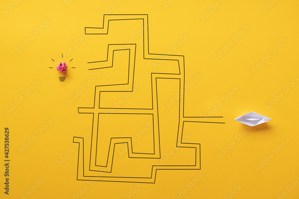 Paper made origami boat trying to get through the maze to the light ...