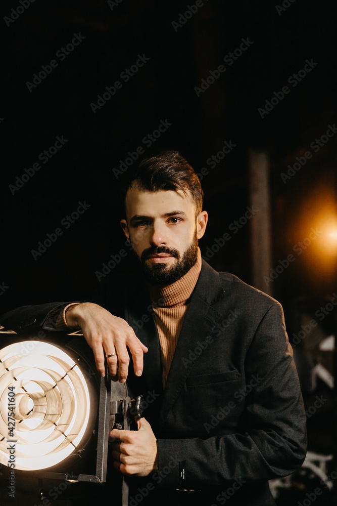 Portrait of a brutal man with lighting fixtures and film equipment at ...