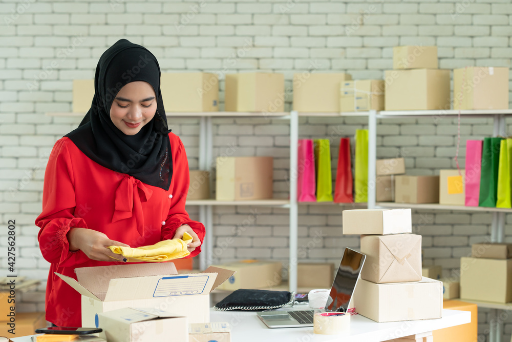 Young Entrepreneur Start-Up, A cheerful female Muslim seller packing an ...