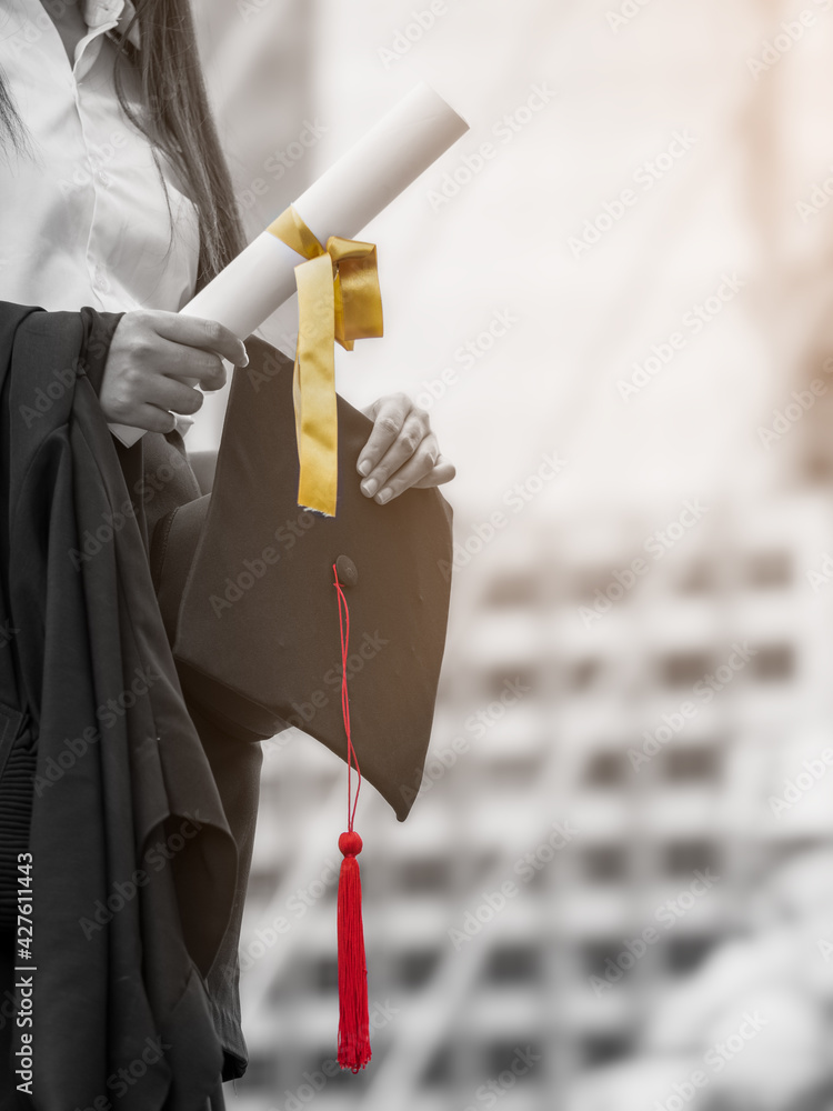 Vertical image, close up graduate holding certificate and grads cap ...