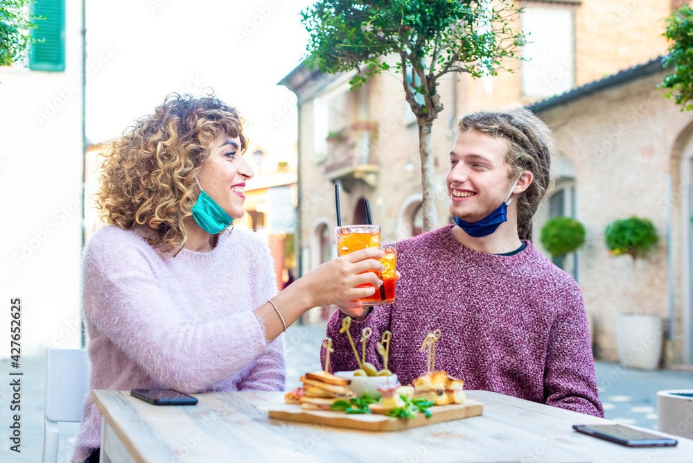 young smiling millenial friends toasting a cocktail in a bar restaurant ...