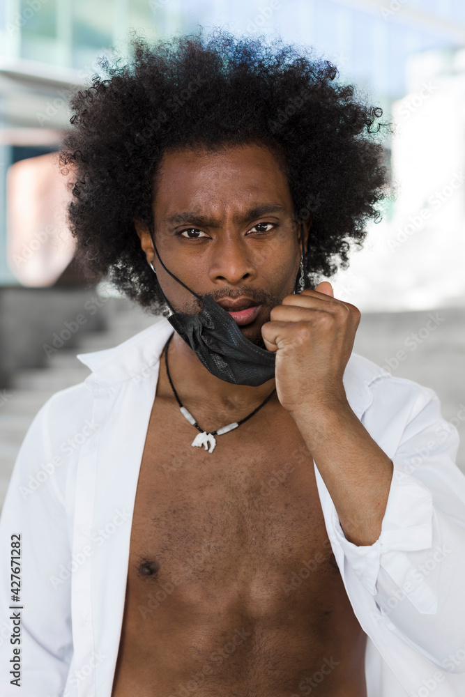 Vertical portrait of black man with afro hair. He is taking off his ...