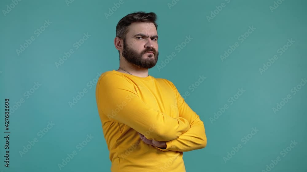 Angry offended man keeping arms crossed and staring at camera with ...