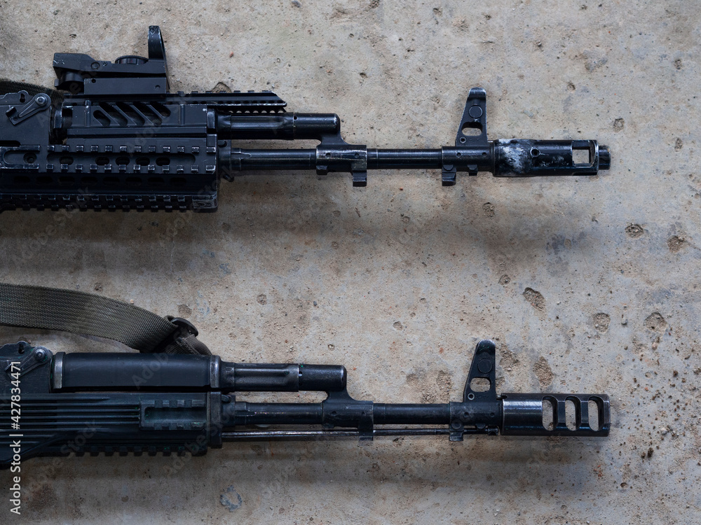 Two custom black assault rifles close-up lying on the concrete floor ...