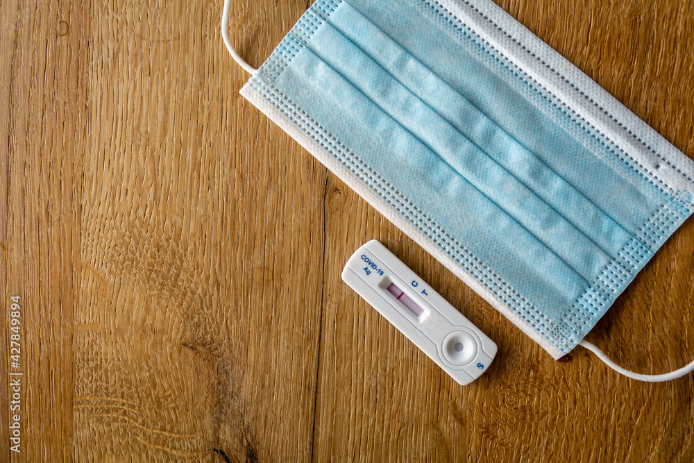 COVID-19 Rapid Antigen Test and a surgical mask on a wooden table ...