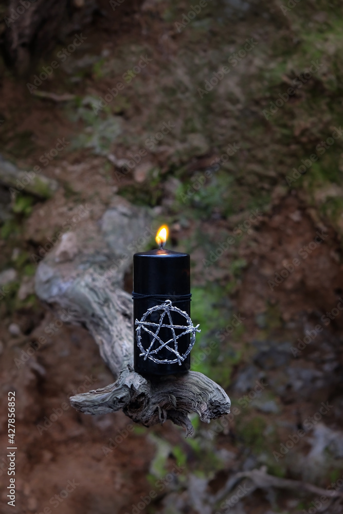 Magic pentagram amulet and black candle in forest. Black magic esoteric ...