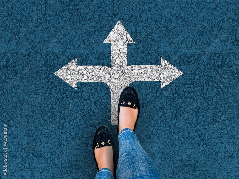 woman legs in shoes standing on road with three direction arrow choices ...