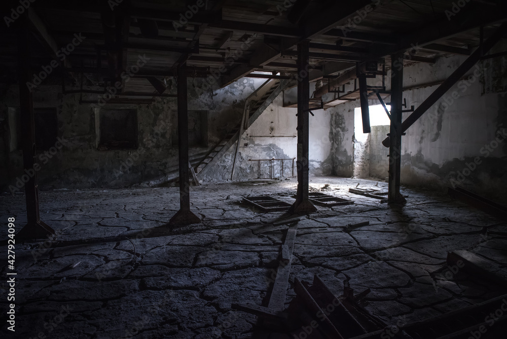 Abandoned industrial interior. Dark room with cracked clay on the floor ...