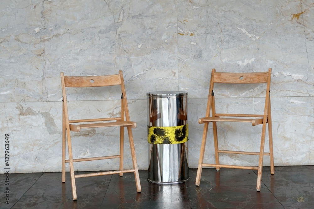 Floor stand ashtray with two empty wooden chairs on the left and the ...