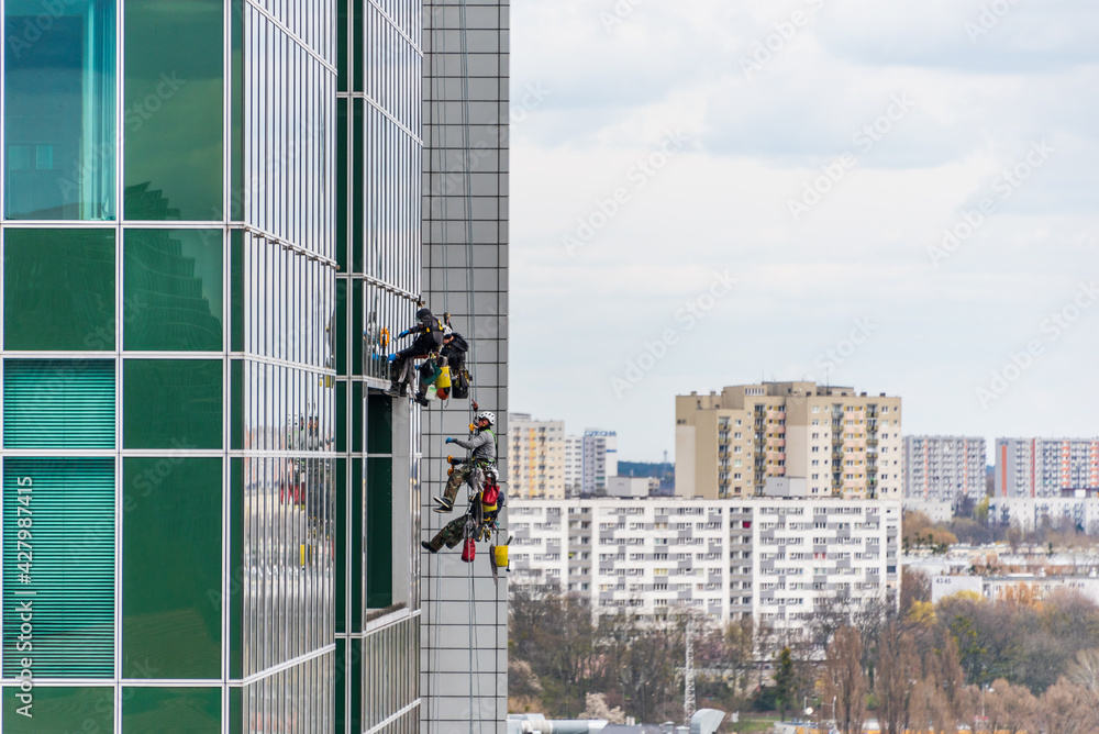 The workers cleaning windows and the glass facade of a modern office ...