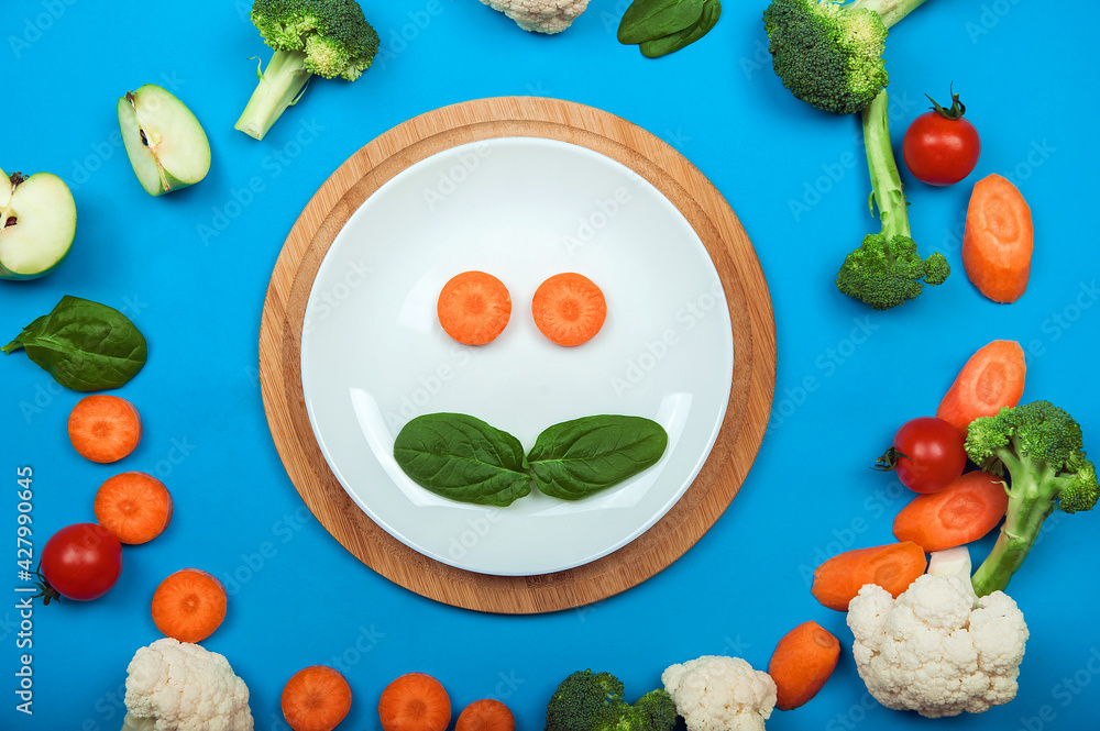 Plate and smiley food on blue background surrounded by fruits and ...
