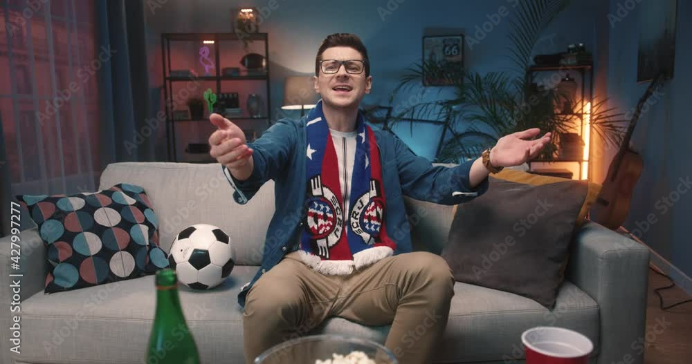 Caucasian young handsome man sitting on couch at home in evening ...