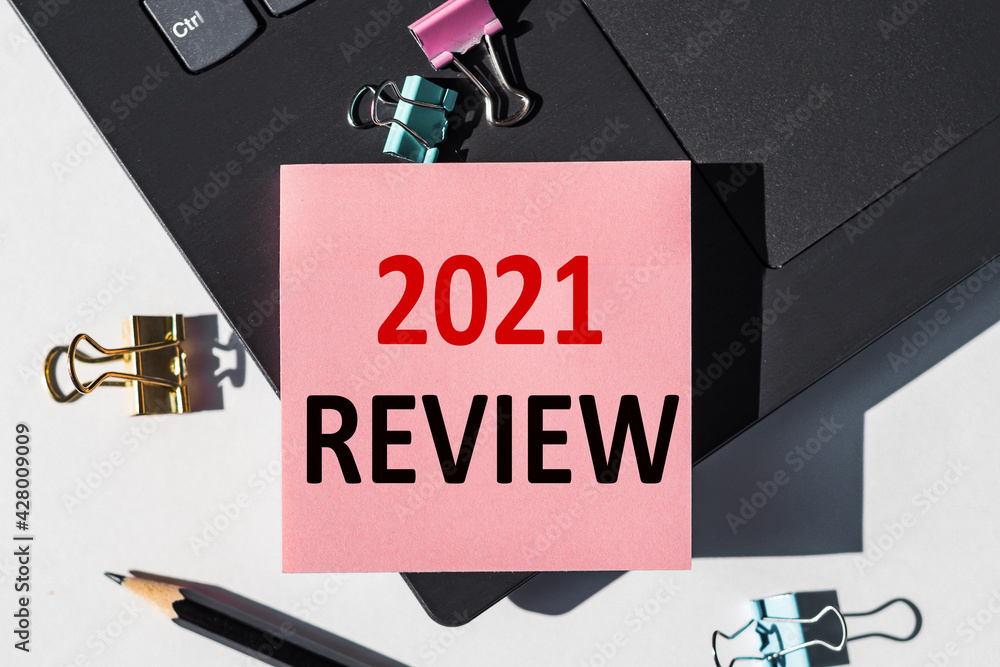 2021 REVIEW text on a small piece of paper. Concept photo - summary of ...