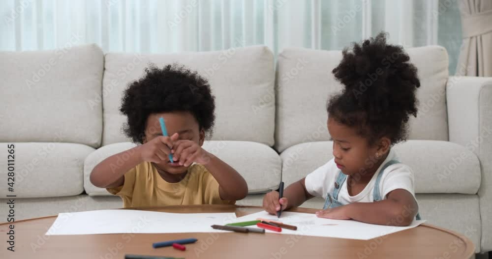 A little adorable African American boy and girl drawing pictures in ...