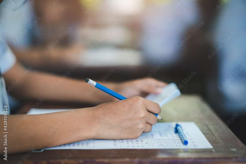 Students writing and reading exam answer sheets exercises in classroom ...