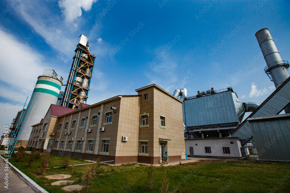 Fotka „Concrete silos and industrial buildings. Plant chimney and ...